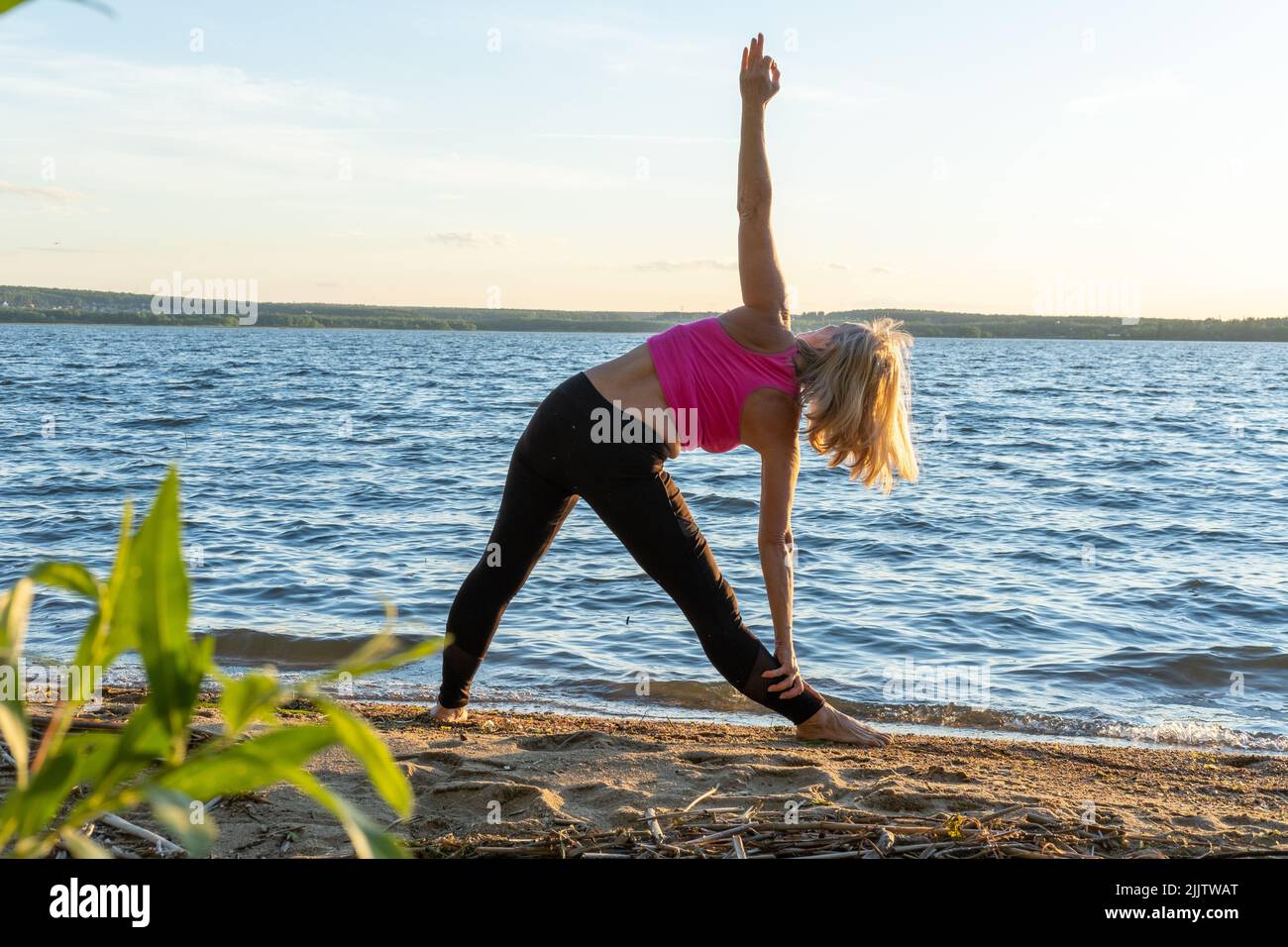 Rear view of a woman tilted sideways. A woman practicing yoga by the ...