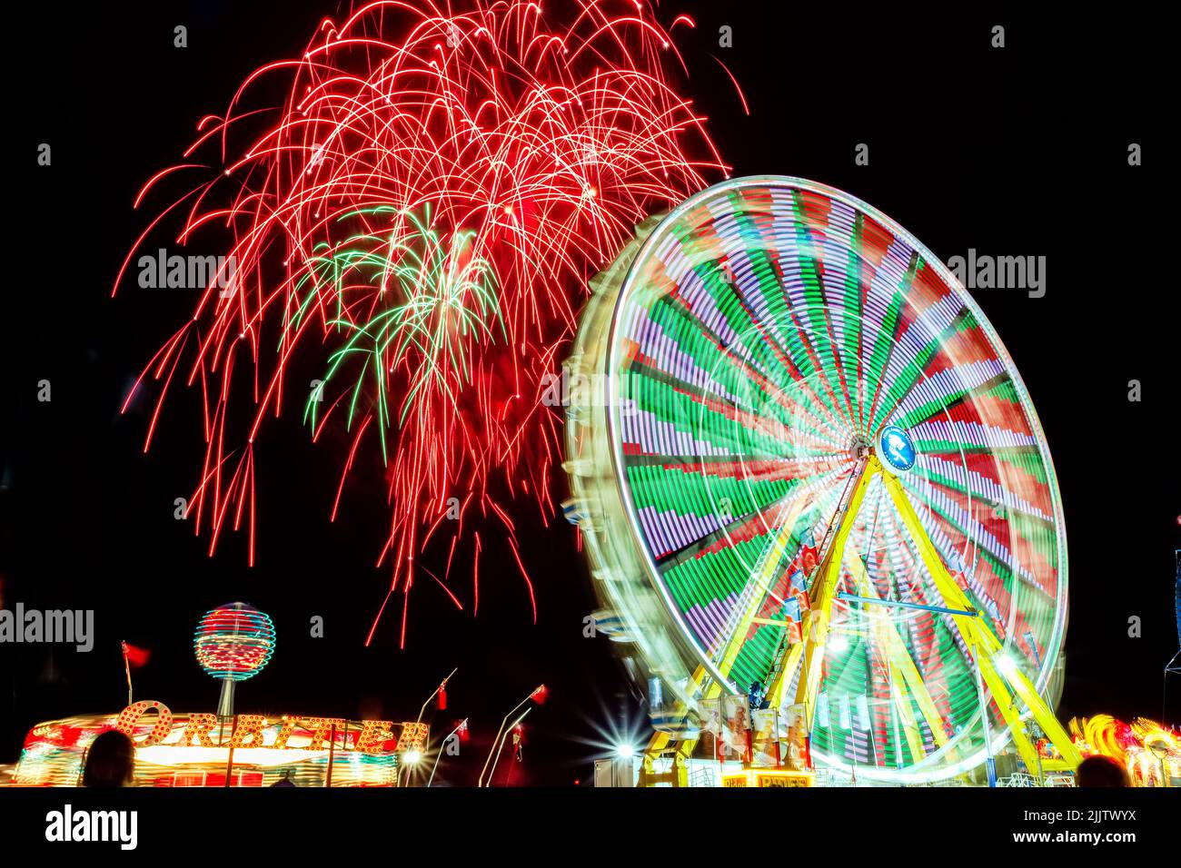 The exploding red fireworks behind an illuminated Ferris wheel at the Red River EX in Winnipeg ...