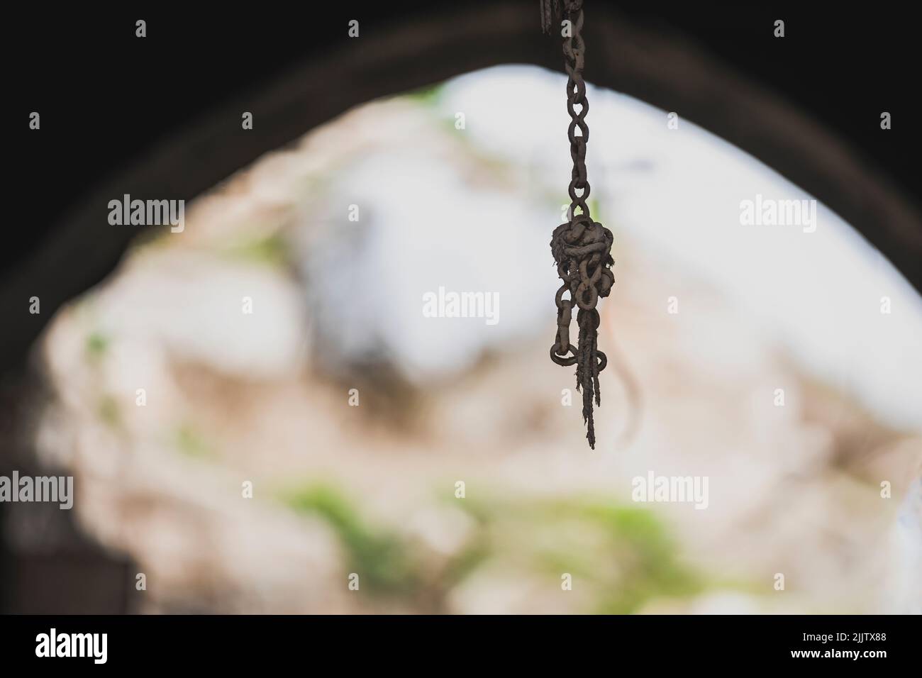 An old rusty metal chain hanging in front of an old gate with bright ...