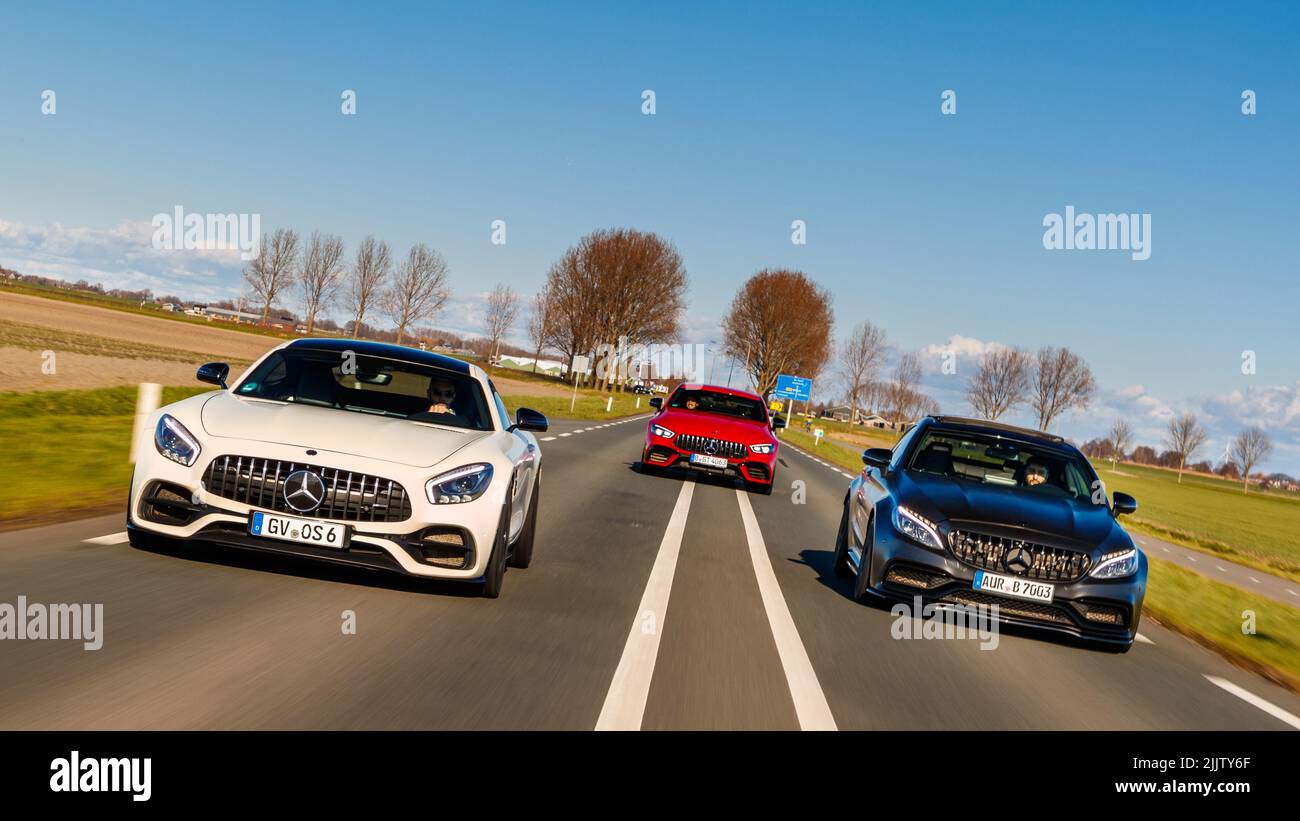 A beautiful 3 Mercedes AMG models driving on the road with autumn trees ...