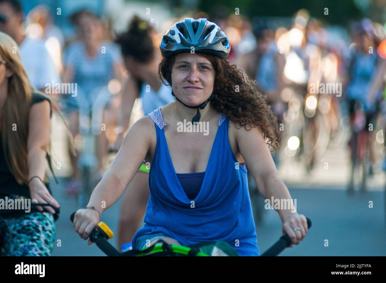 A young female biker with curly hair riding on a bicycle during the ...