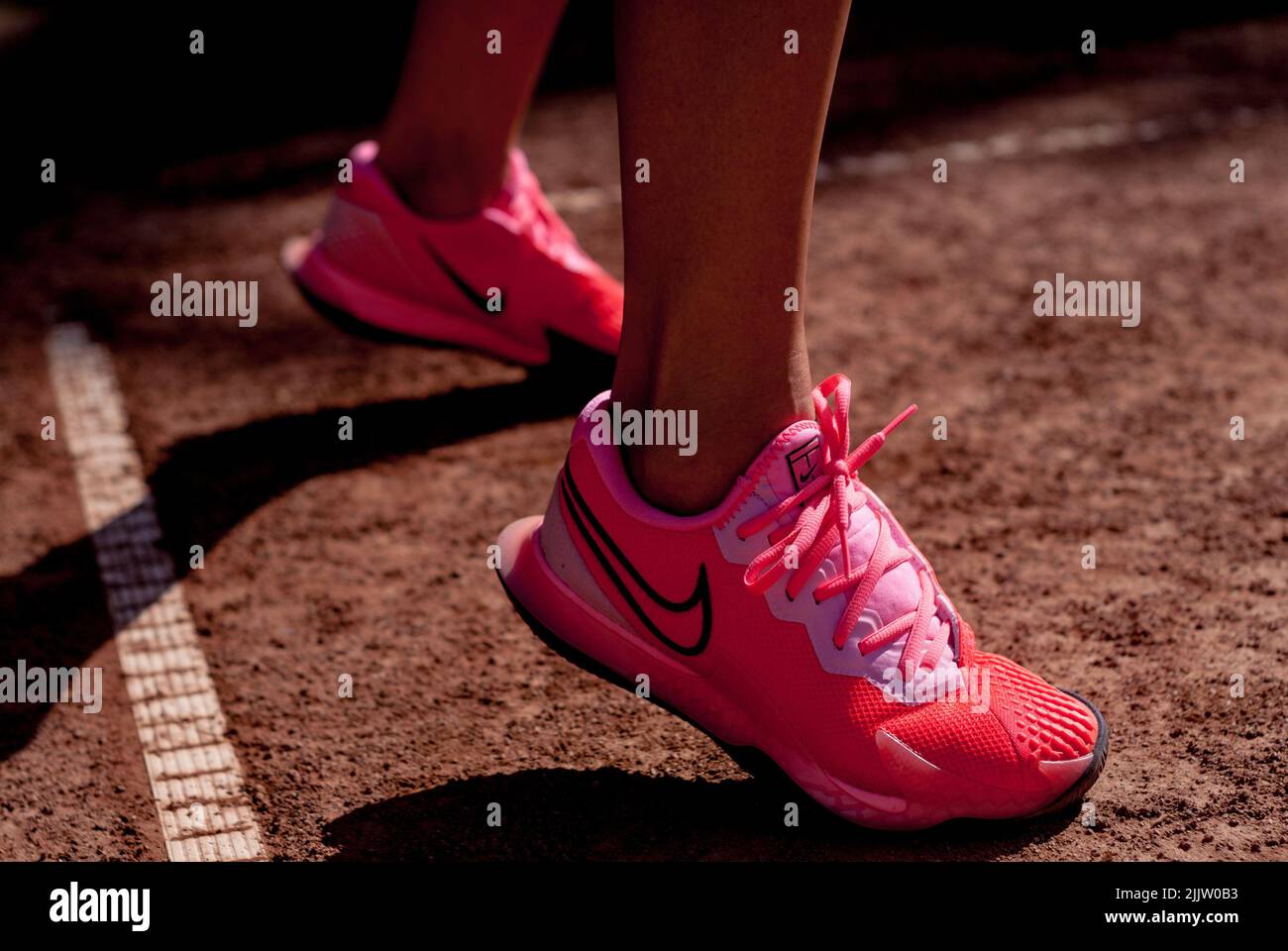 A closeup shot of a athlete legs in red shoes on the tennis court ...
