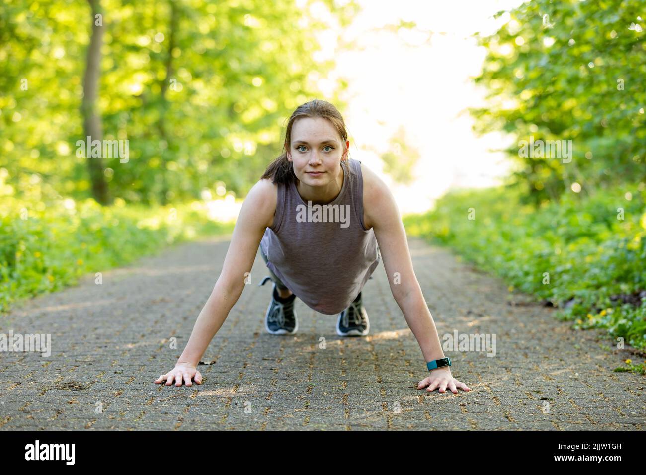 A athletic young woman makes fitness workout in nature a public park ...