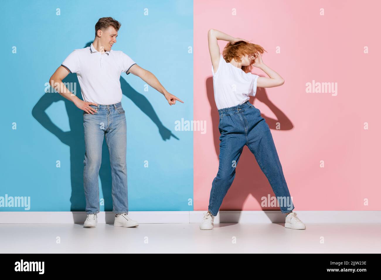 Portrait of young cheerful couple dancing, posing isolated over pink ...