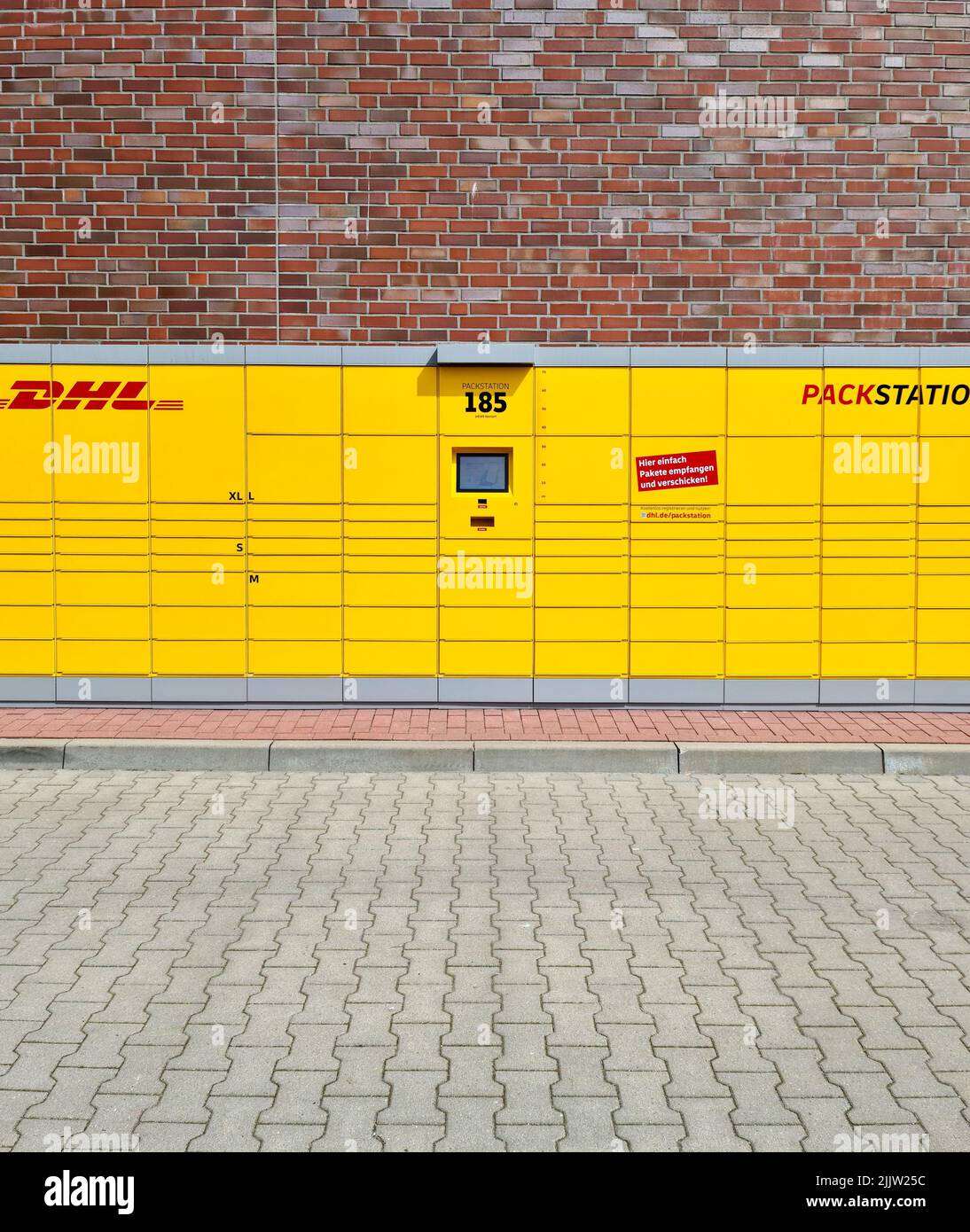A yellow parcel station of the German parcel service DHL in front of a ...