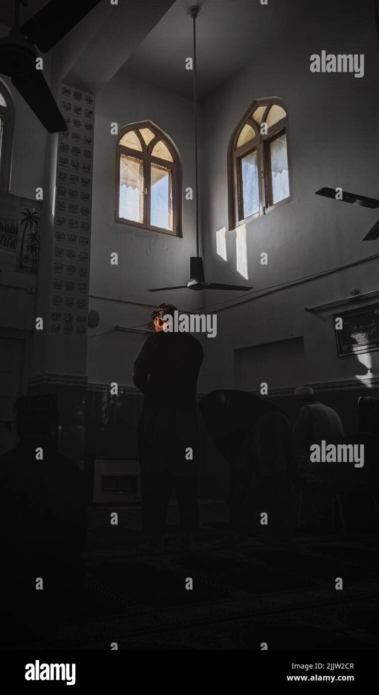 A vertical back view of a male worshipper praying in the Masjid Ashra ...
