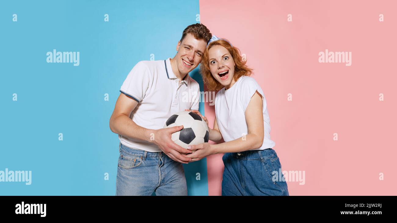 Portrait of young joyful couple, football fans posing with ball ...