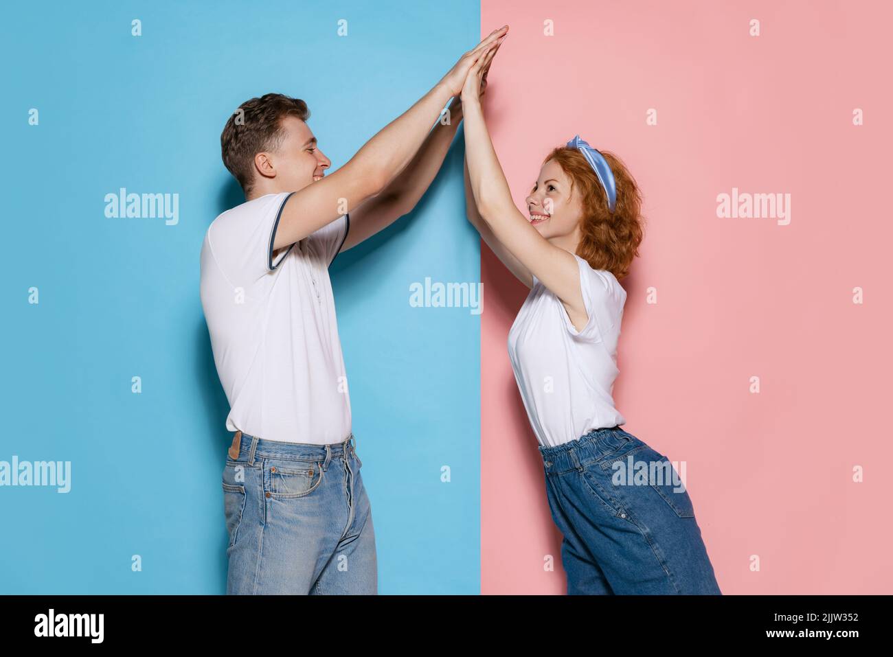 Portrait of young excited couple, giving high five isolated over pink ...