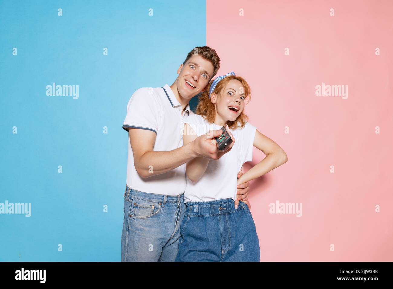 Portrait of young couple with funny expression turning on TV isolated ...