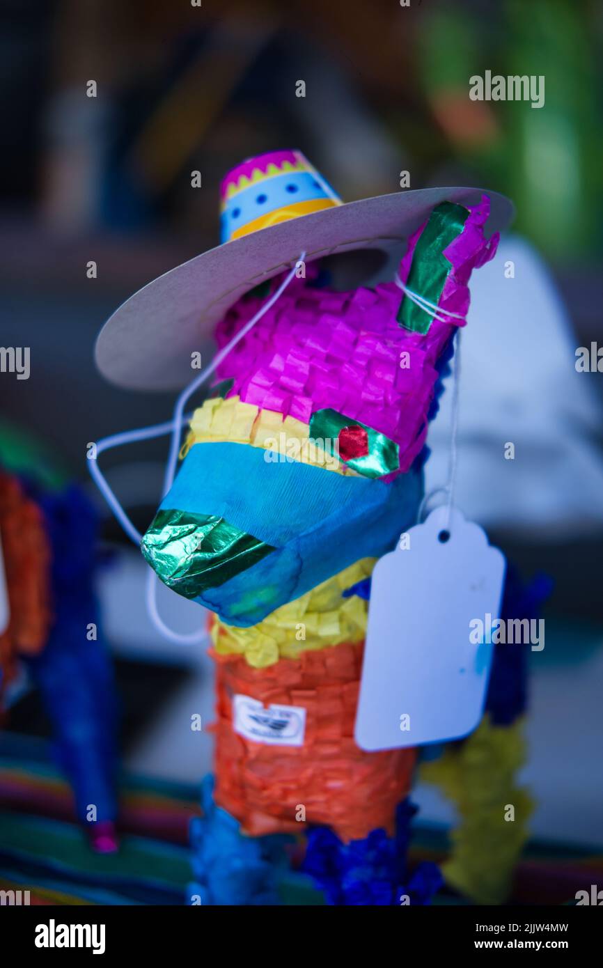 A vertical shot of a small Mexican pinata of a horse with a tiny hat ...