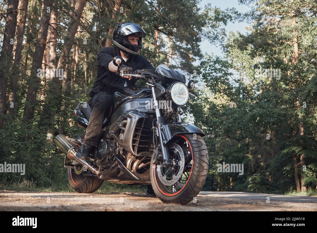 Young male biker in a helmet travels on a motorcycle alone, on a road ...