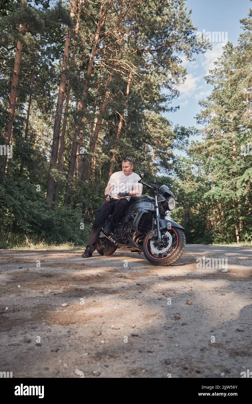 Young male biker travels on a motorcycle alone, stopped and smoking on ...