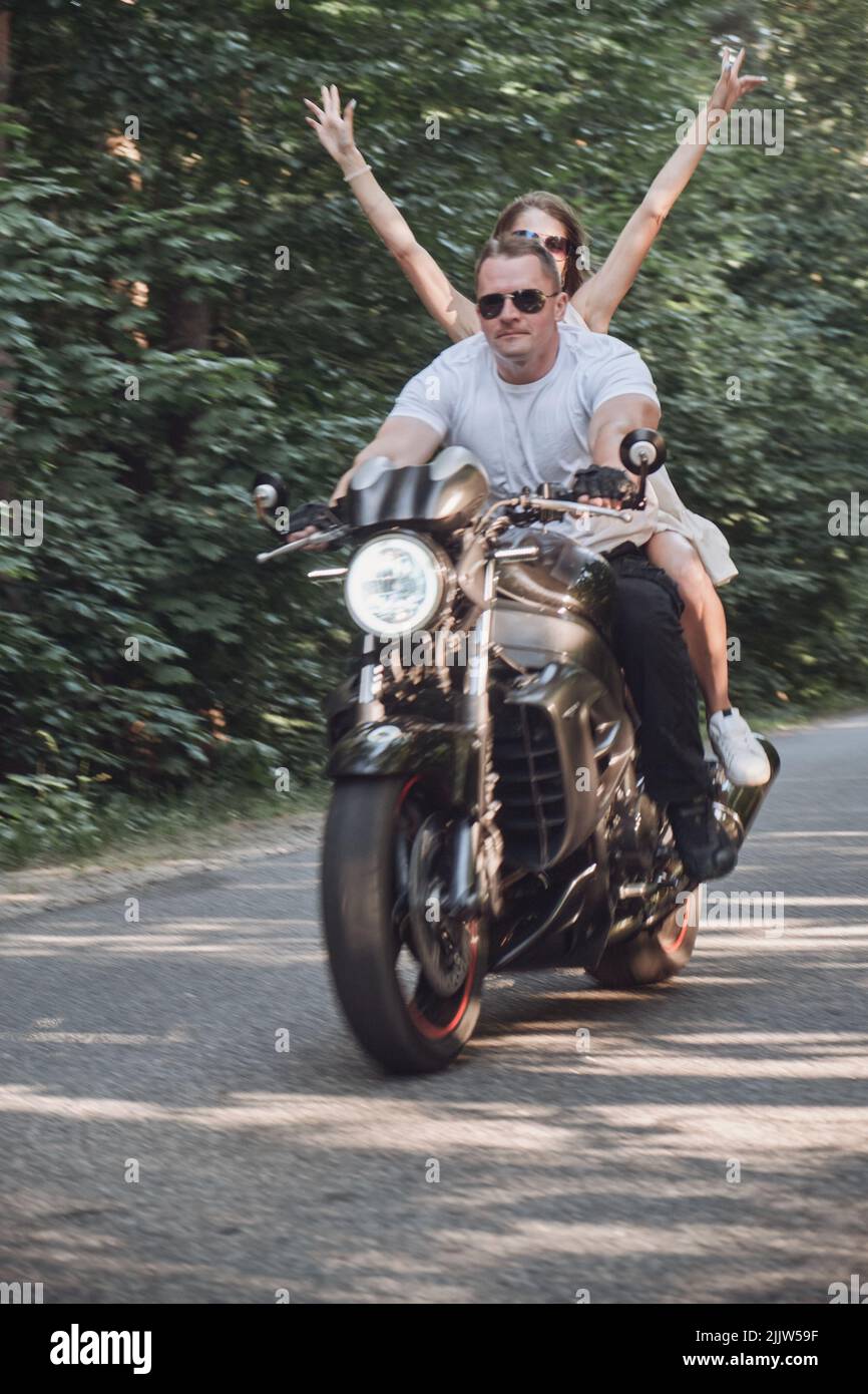 A young happy couple rides a motorcycle on an asphalt road in the ...