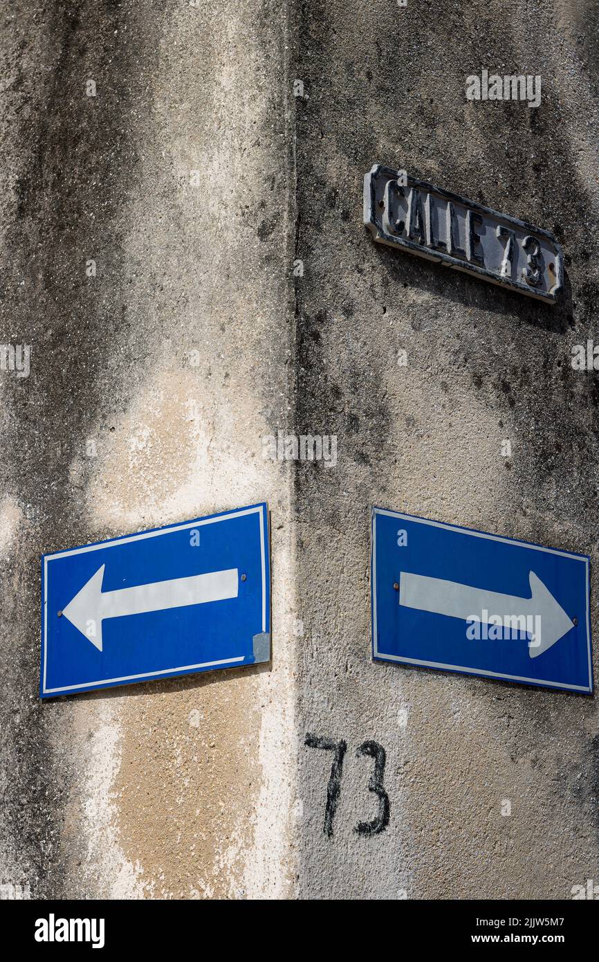 A vertical shot of road signs on a wall showing right and left on Cuban ...