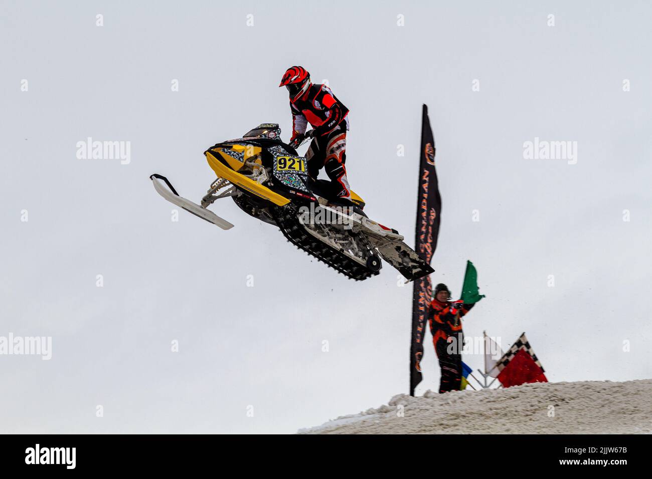 Snowmobiler jumping high above the track. On a snowmobile, a sportsman ...
