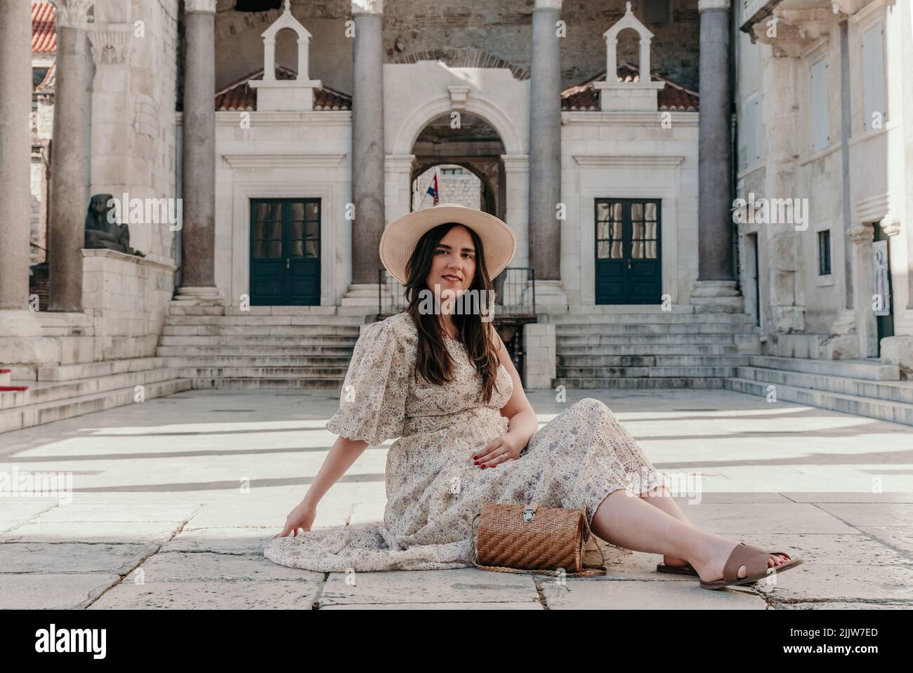 A closeup of a beautiful woman sitting on peristyle of the amazing ...