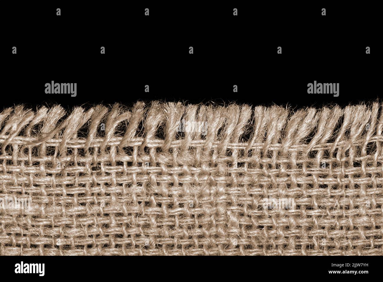 Closeup of burlap hessian sacking. Texture canvas fabric isolated on black background. Light ...