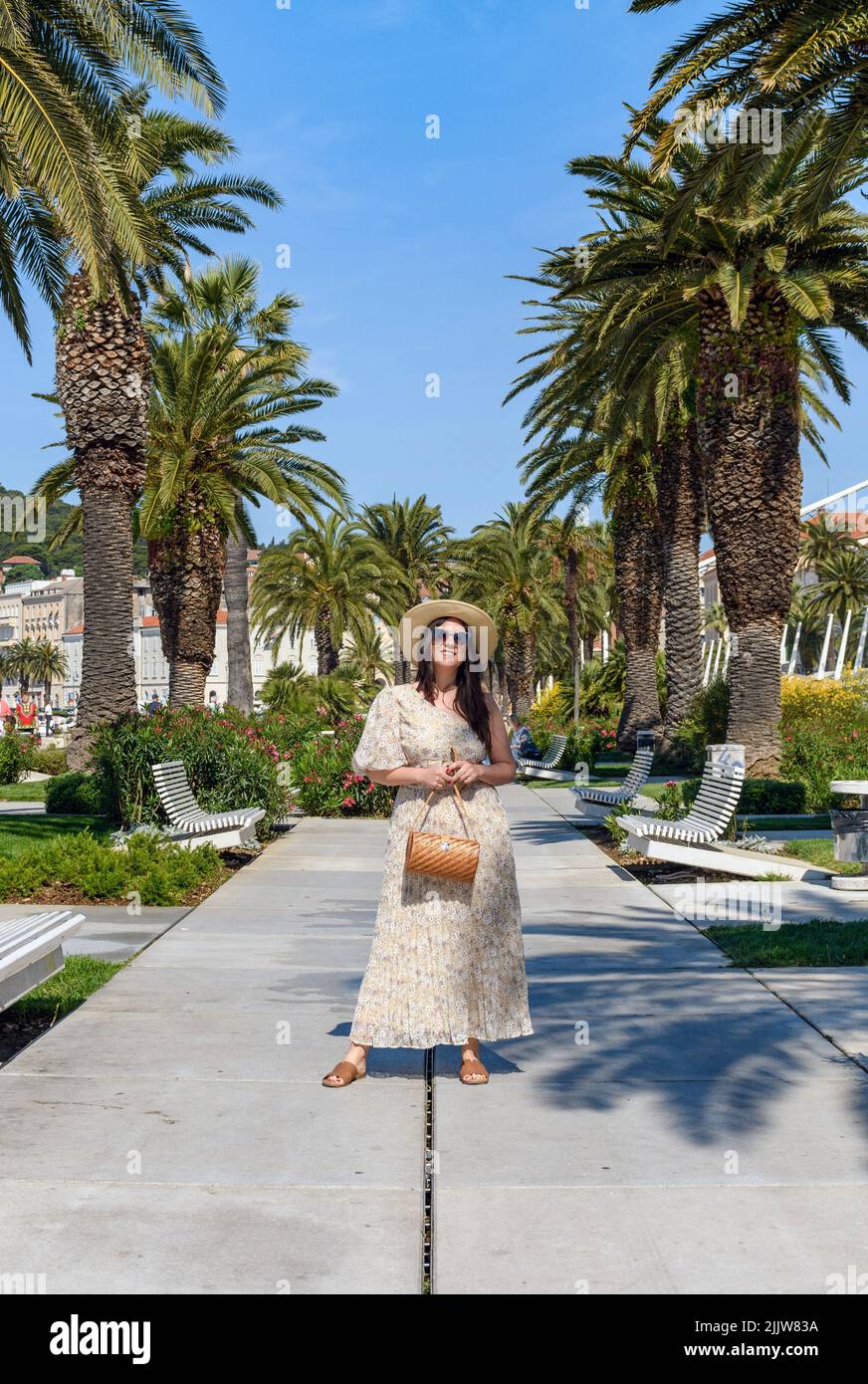 A vertical shot of a Caucasian woman wearing a summer style dress on a ...