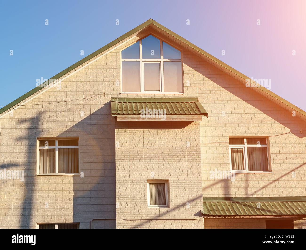 A private mansion made of beige bricks lit by the sun under a clear sky ...