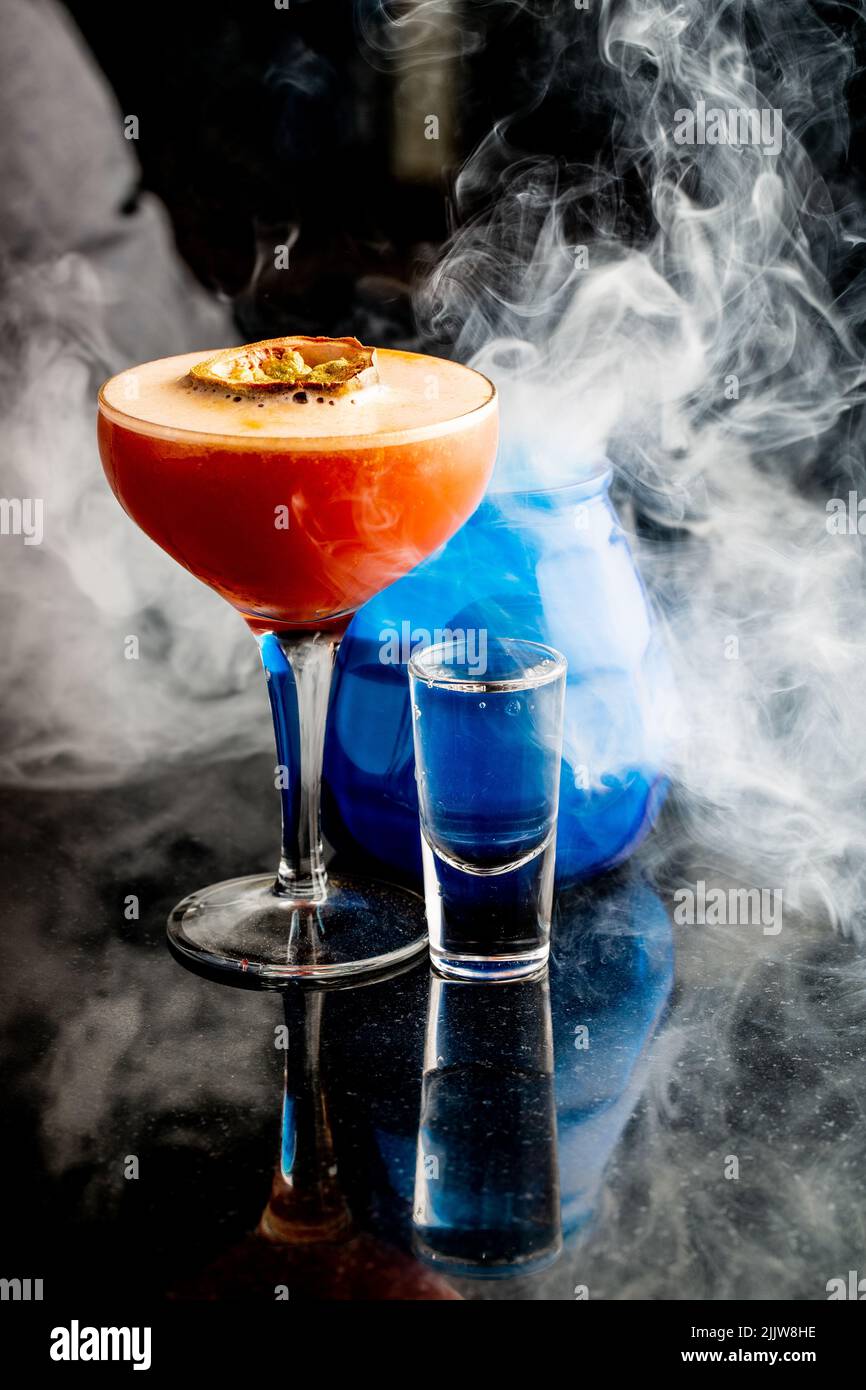 A vertical shot of an alcoholic cocktail surrounded by smoke on a ...