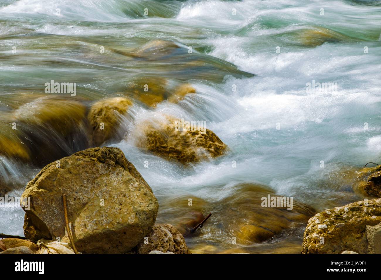 The rocks in a stream with smooth flowing water Stock Photo - Alamy