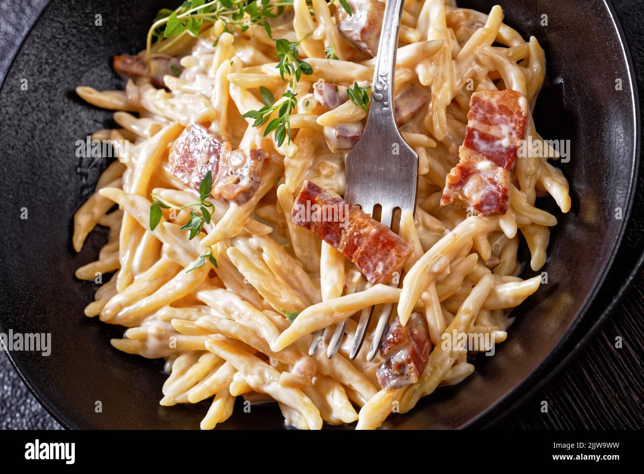 close-up of capunti pasta in cream pecorino cheese and pancetta sauce ...