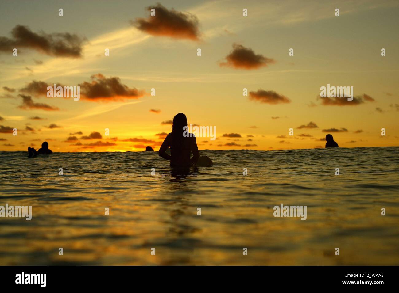 A female surfer waiting for waves at sunset in Sumatra, Indonesia Stock Photo - Alamy