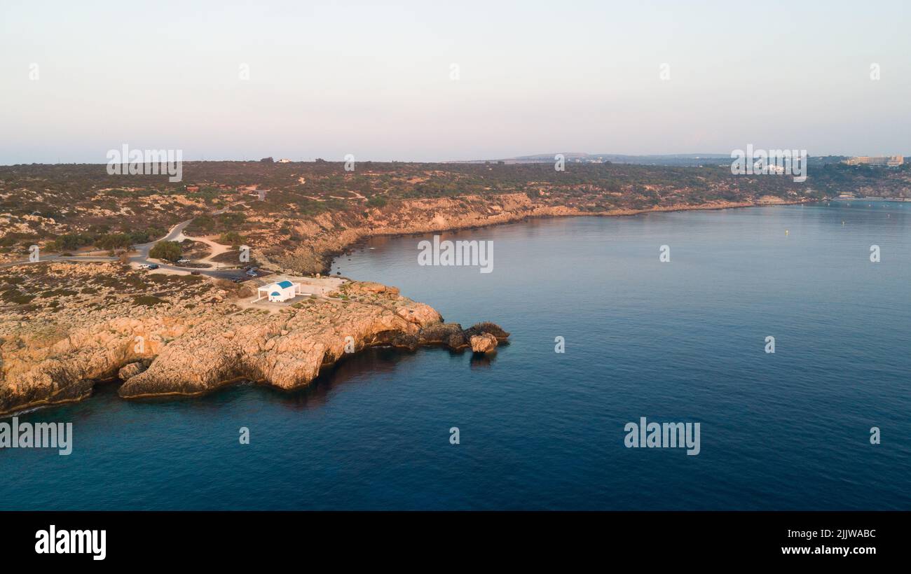 Aerial view of coastline sunset and landmark white washed chapel Agioi ...