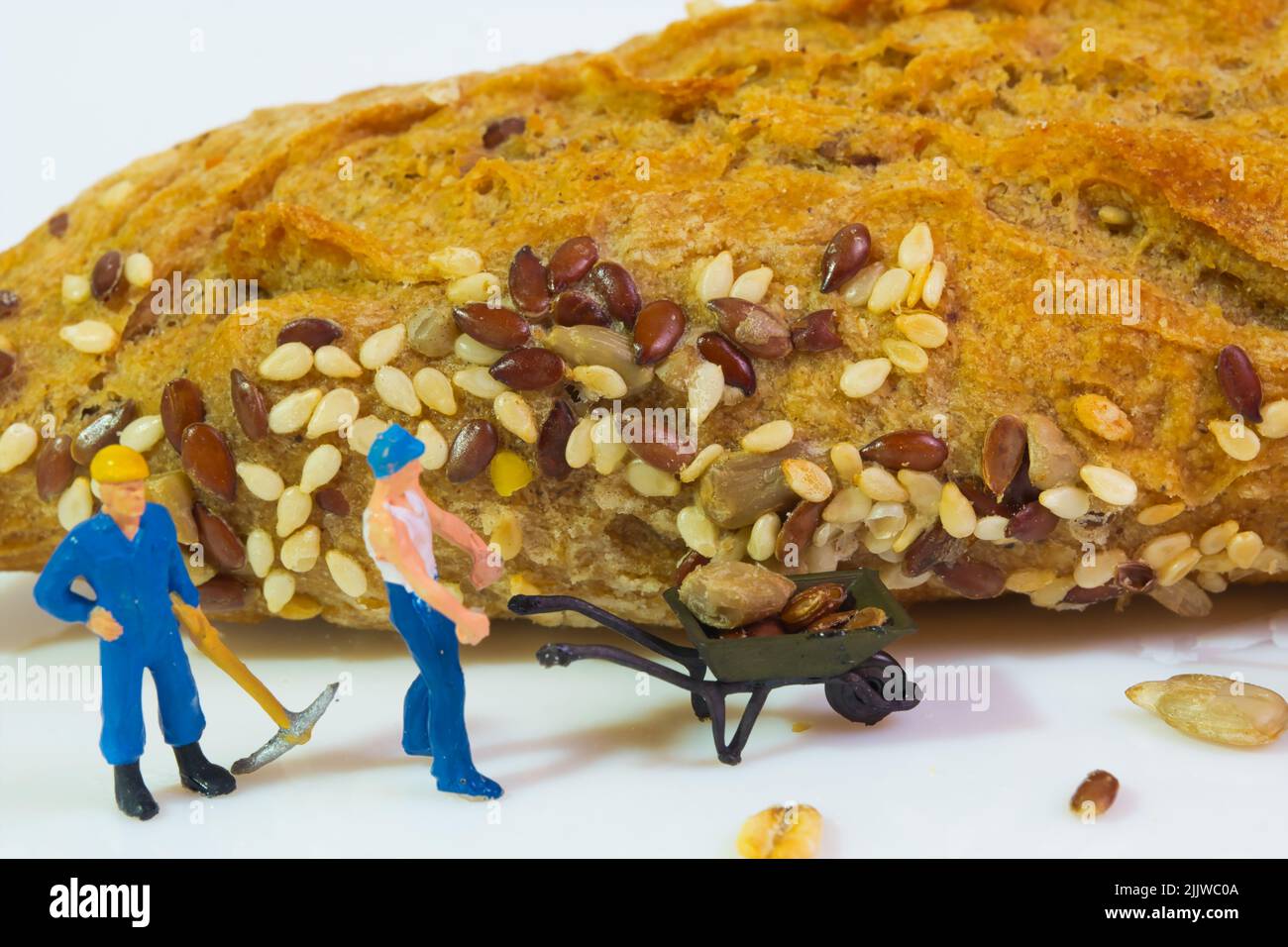 worker with wheelbarrow in front of a fresh bread with grains, white ...