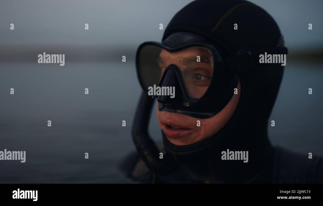 Young scuba diver looking away while submerged in sea water ...