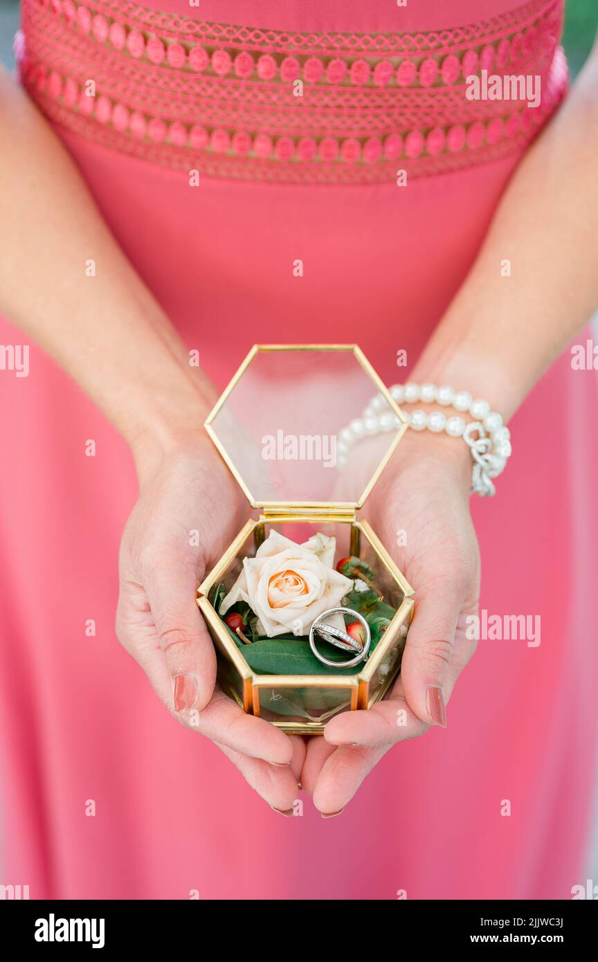 A vertical shot of human hands holding little box with wedding rings ...