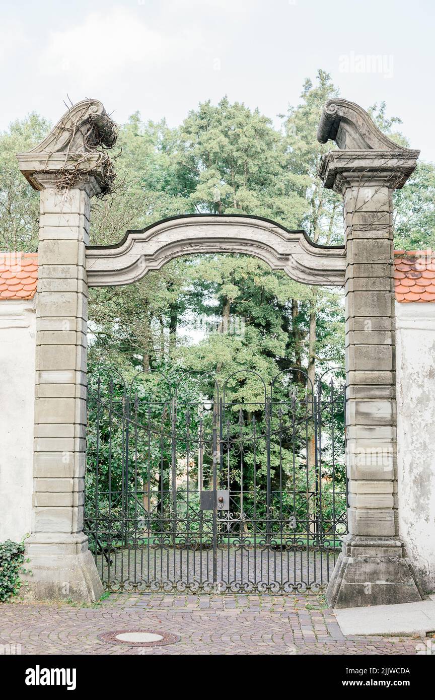 A vertical shot of park entrance with metal gates surrounded by growing ...