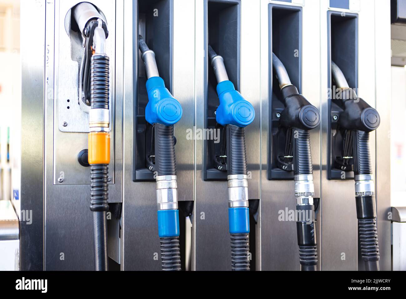 Five black, blue and orange fuel hoses at a gas station. Concept of ...