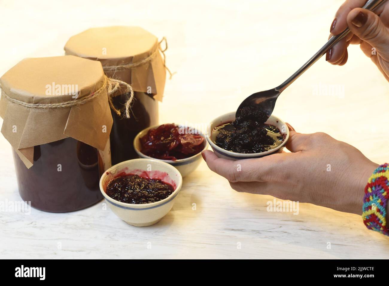 A hand serving homemade mulberry jam in small bowls from jars Stock ...