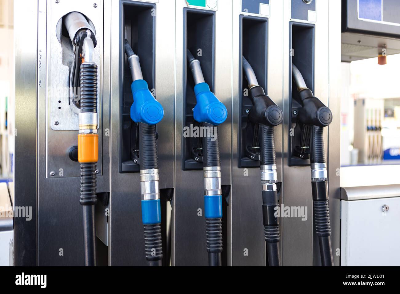 Five black, blue and orange fuel hoses at a gas station. Concept of ...