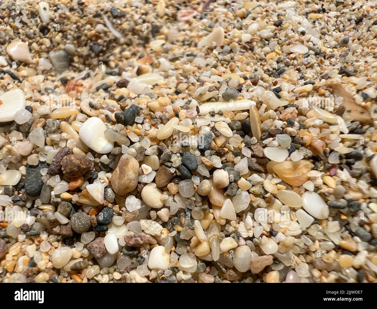 Sandy background with small stones on the beach Stock Photo - Alamy