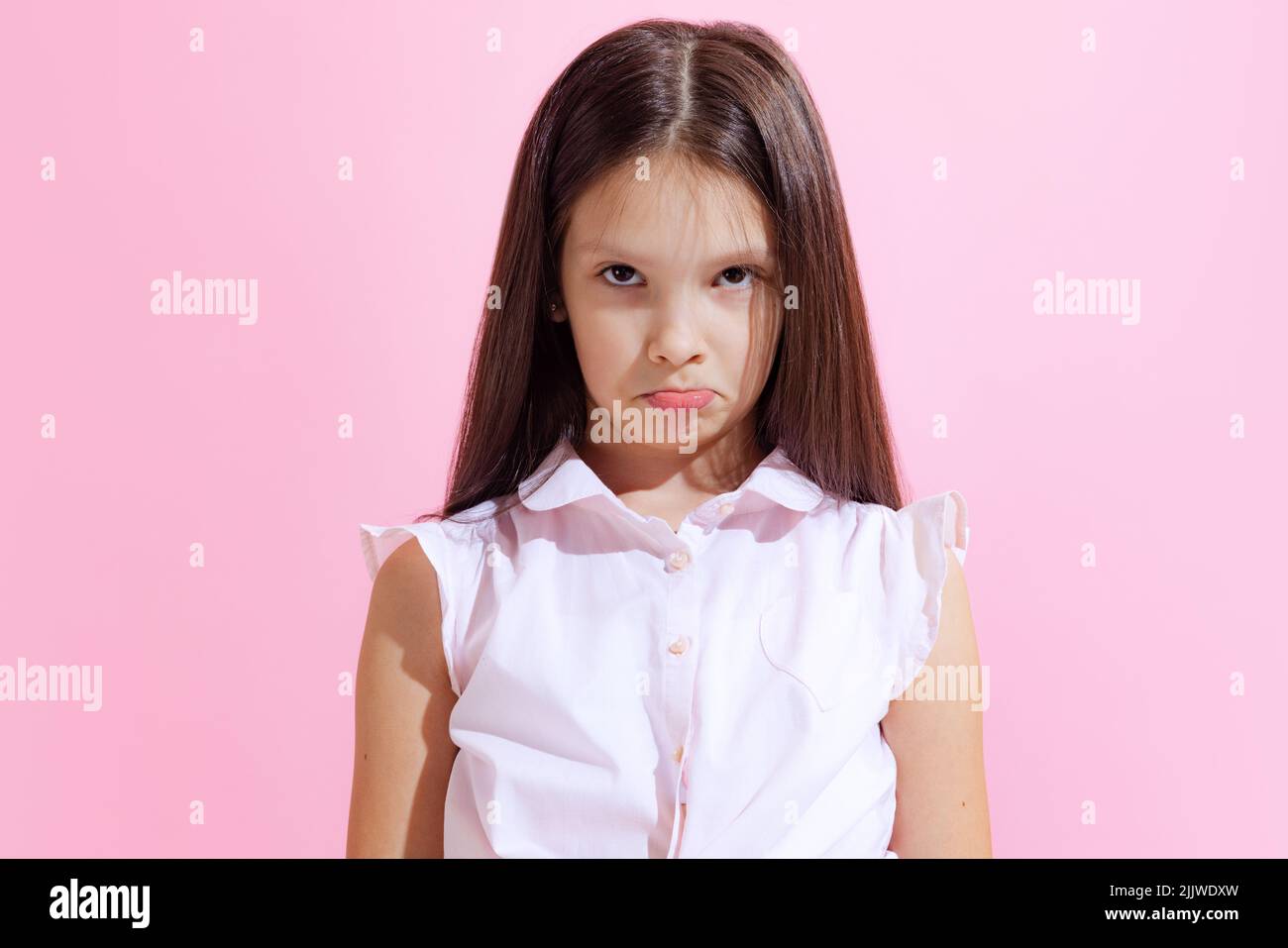 Portrait of little cute offended girl, kid in blouse isolated on pink ...