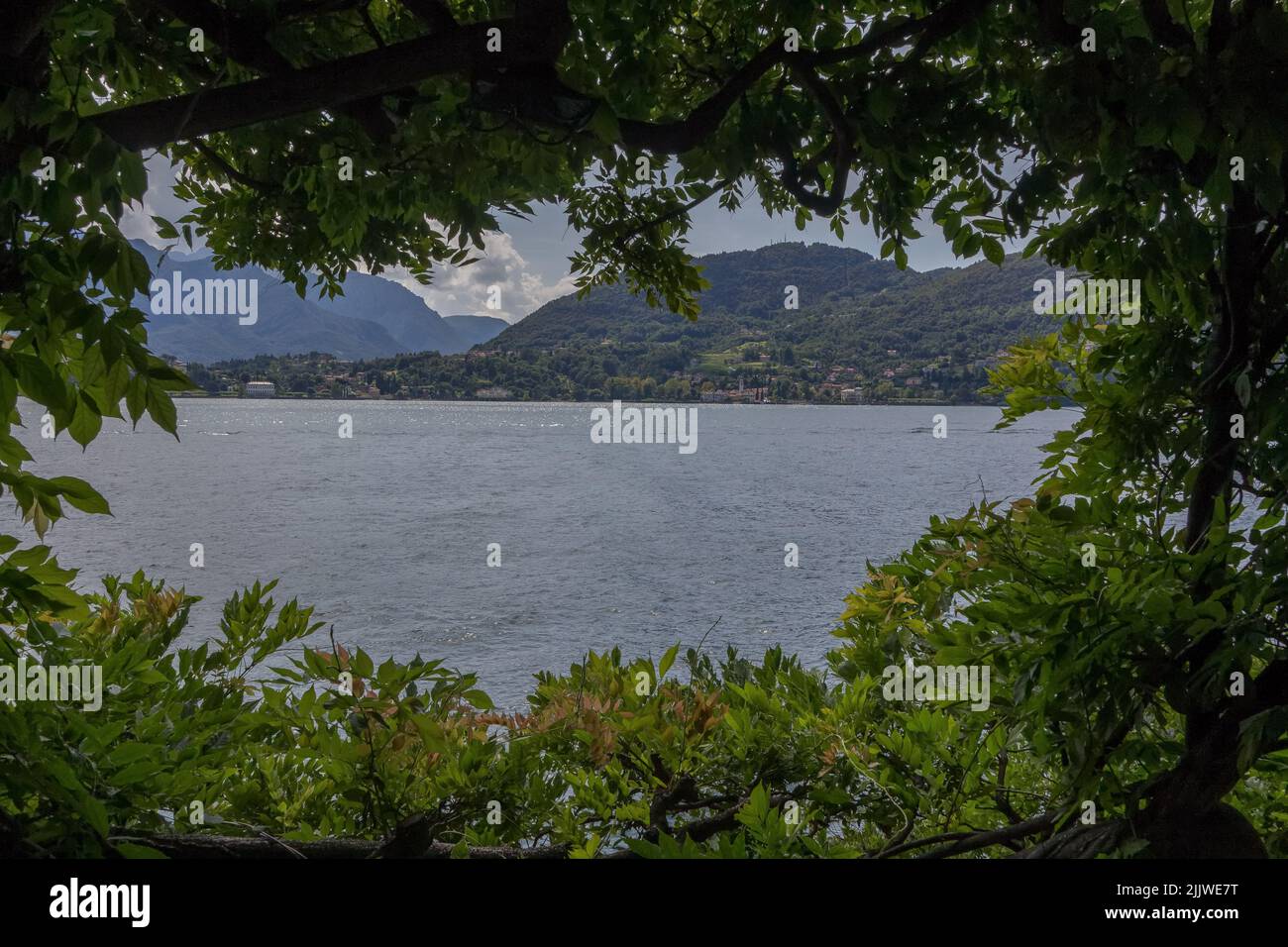 A beautiful view of Lake Como through green leaves in Italy Stock Photo ...