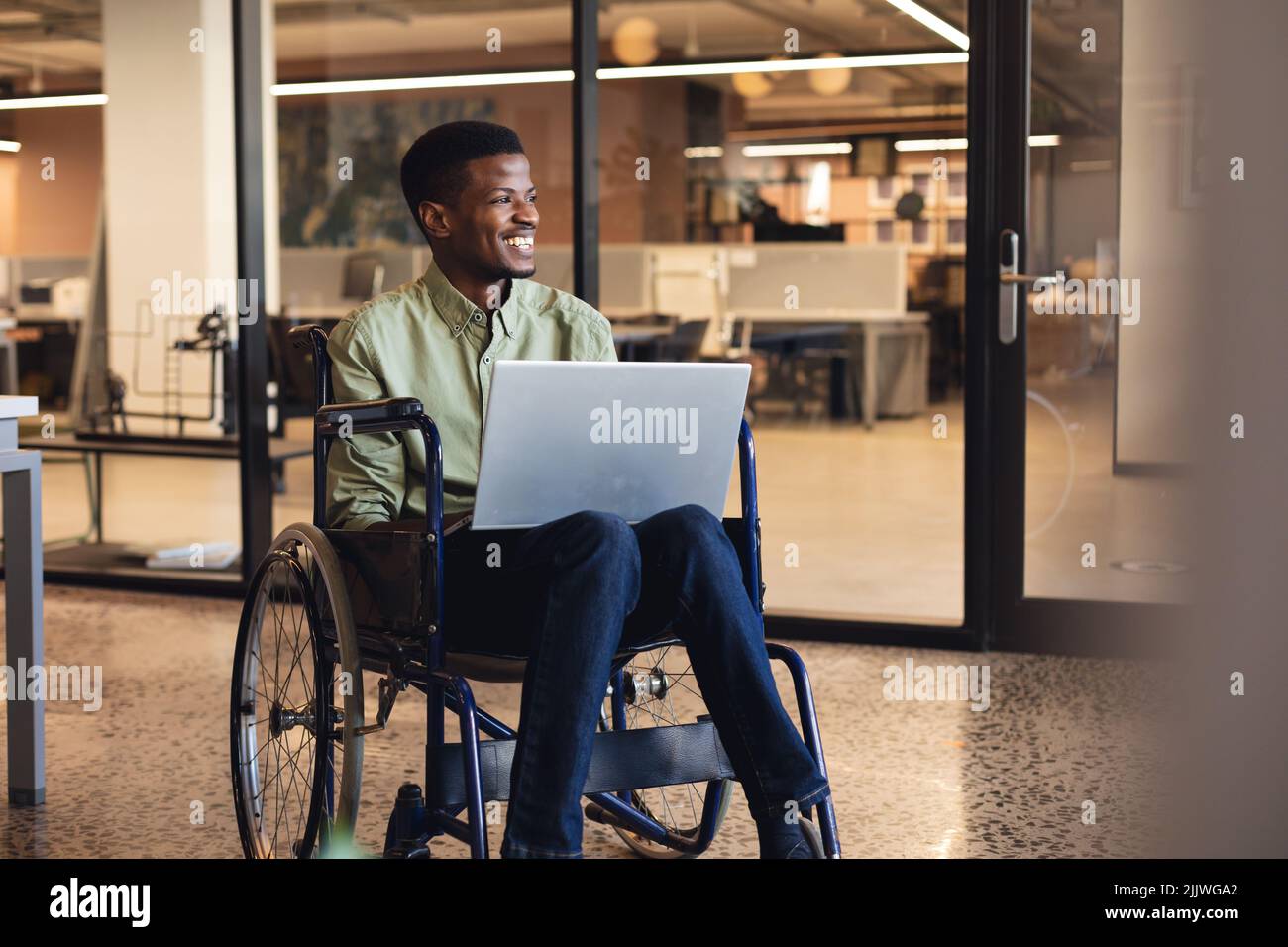 Smiling african american businessman with disability using laptop in ...