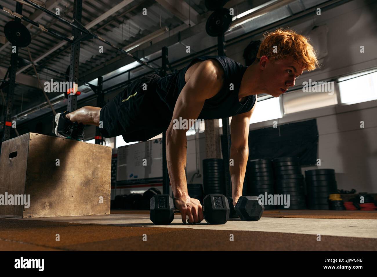 Portrait of young muscular red-headed man doing push up exercises with ...