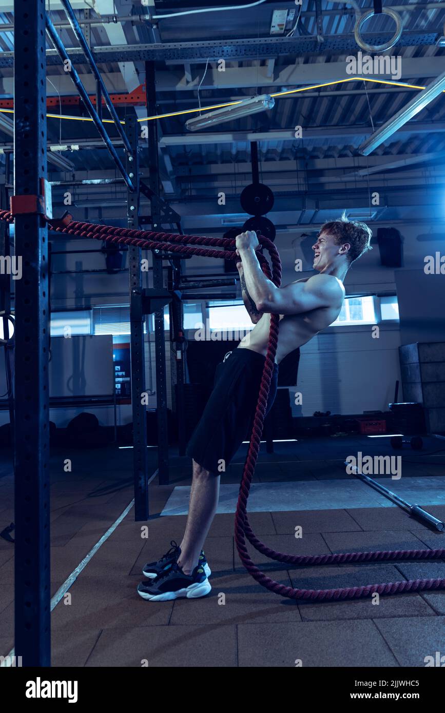 Full-length portrait of muscular red-haired man training, doing ...