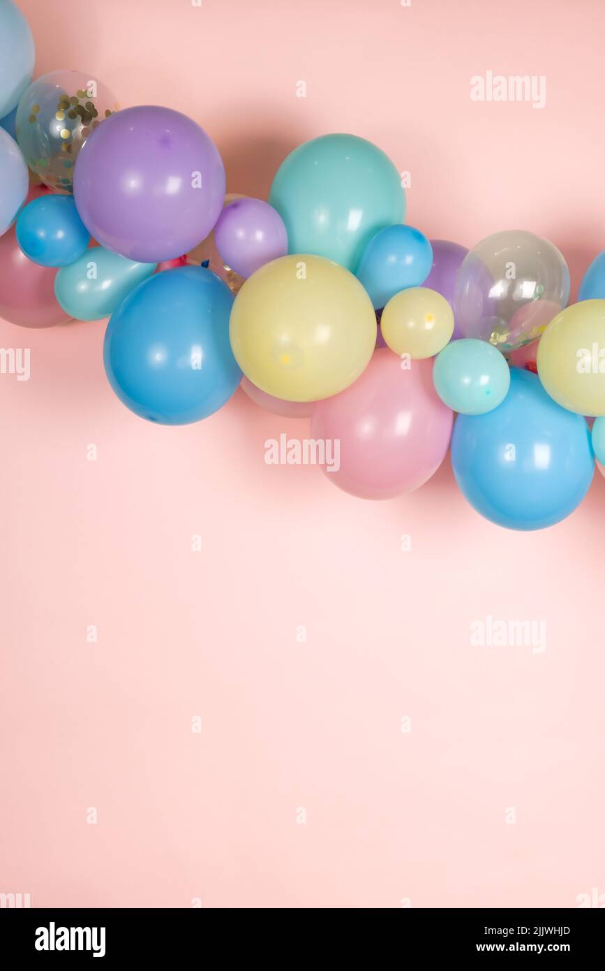 A soft pastel balloon garland against a light baby pink background ...