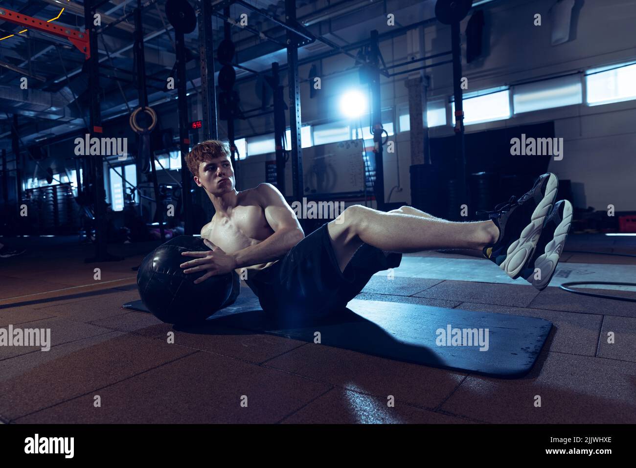 Portrait of young sportive, muscular man doing press exercises with ...