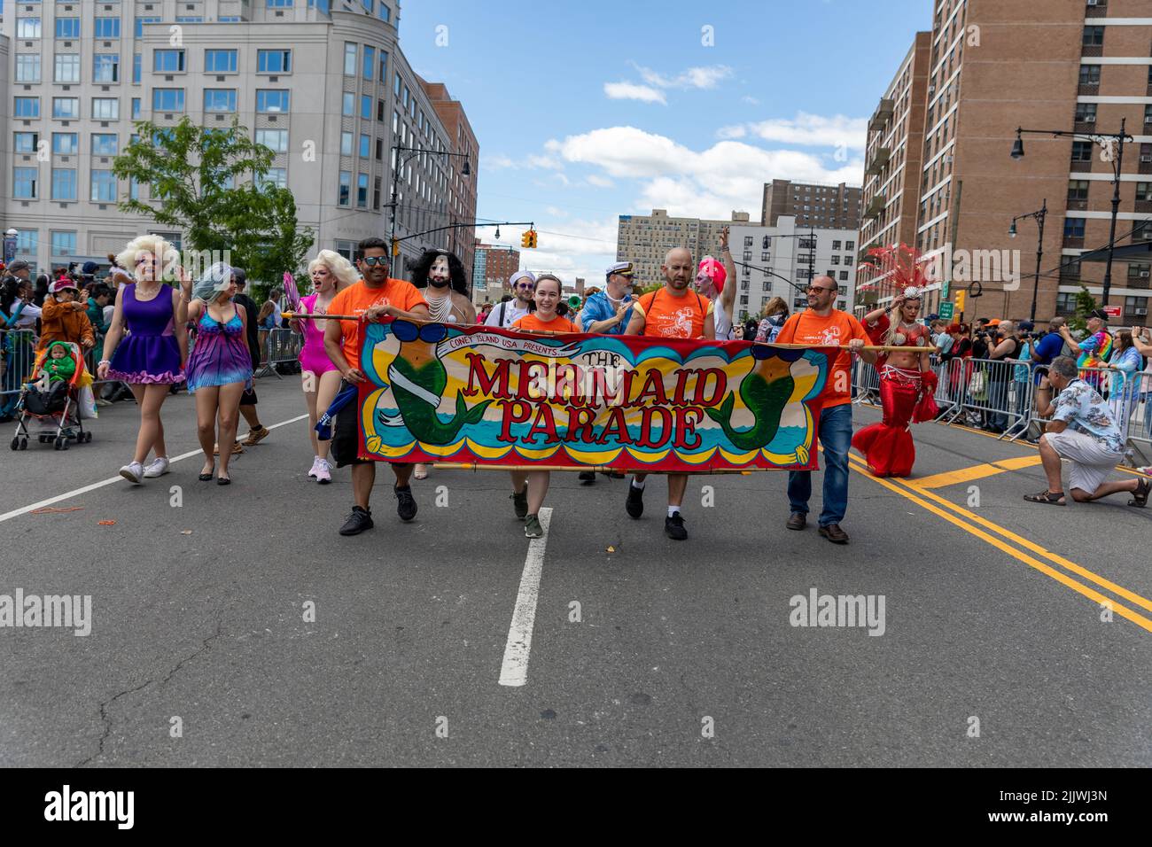 A shot of men with a poster dedicated to the 40th Annual Mermaid Parade ...