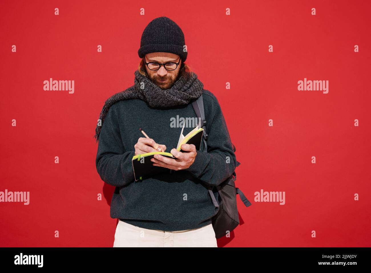 White man wearing warm clothes writing down notes in planner isolated ...