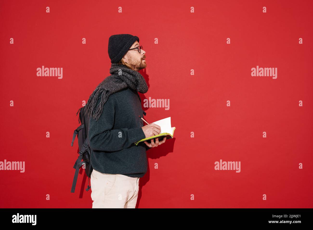 White man wearing warm clothes writing down notes in planner isolated ...