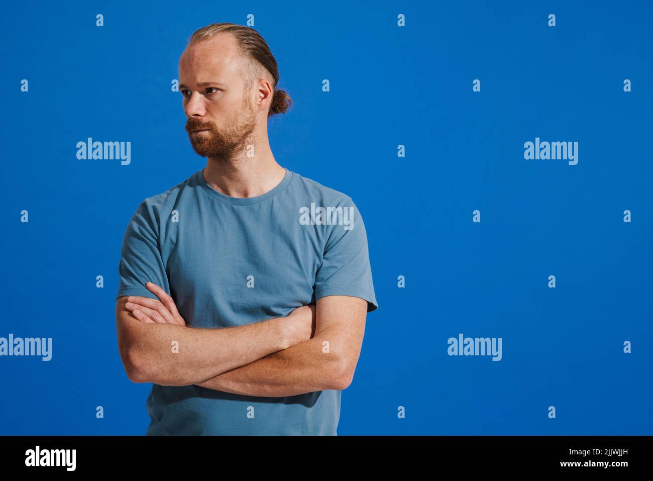 Ginger white man with beard posing with arms crossed isolated over blue ...