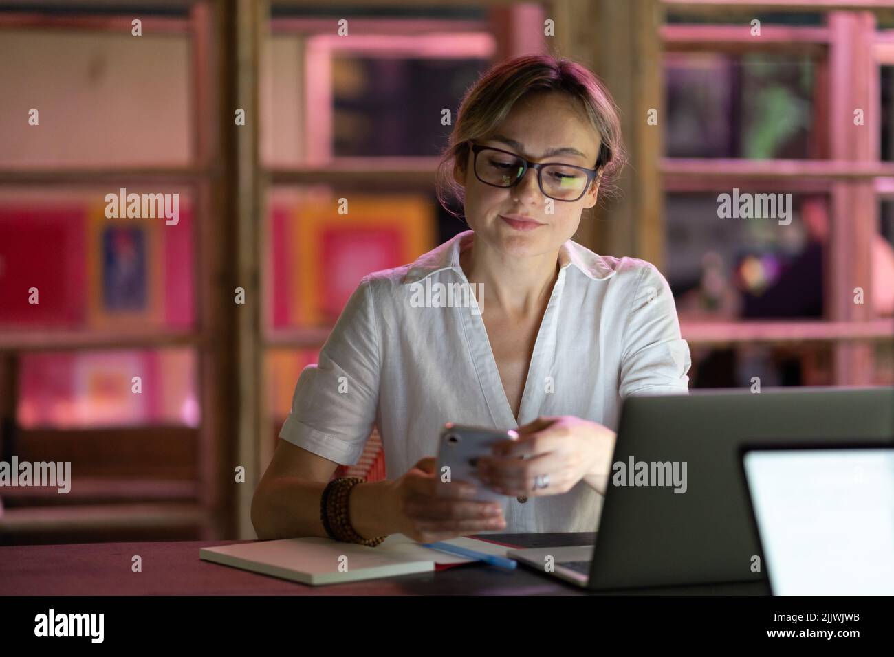 Female employee using mobile device at workplace, young woman ...