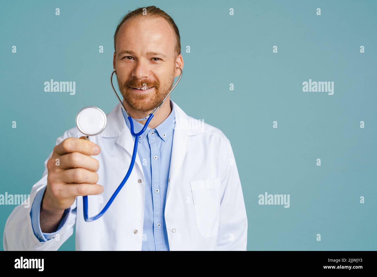 White male doctor wearing lab coat smiling and showing stethoscope ...