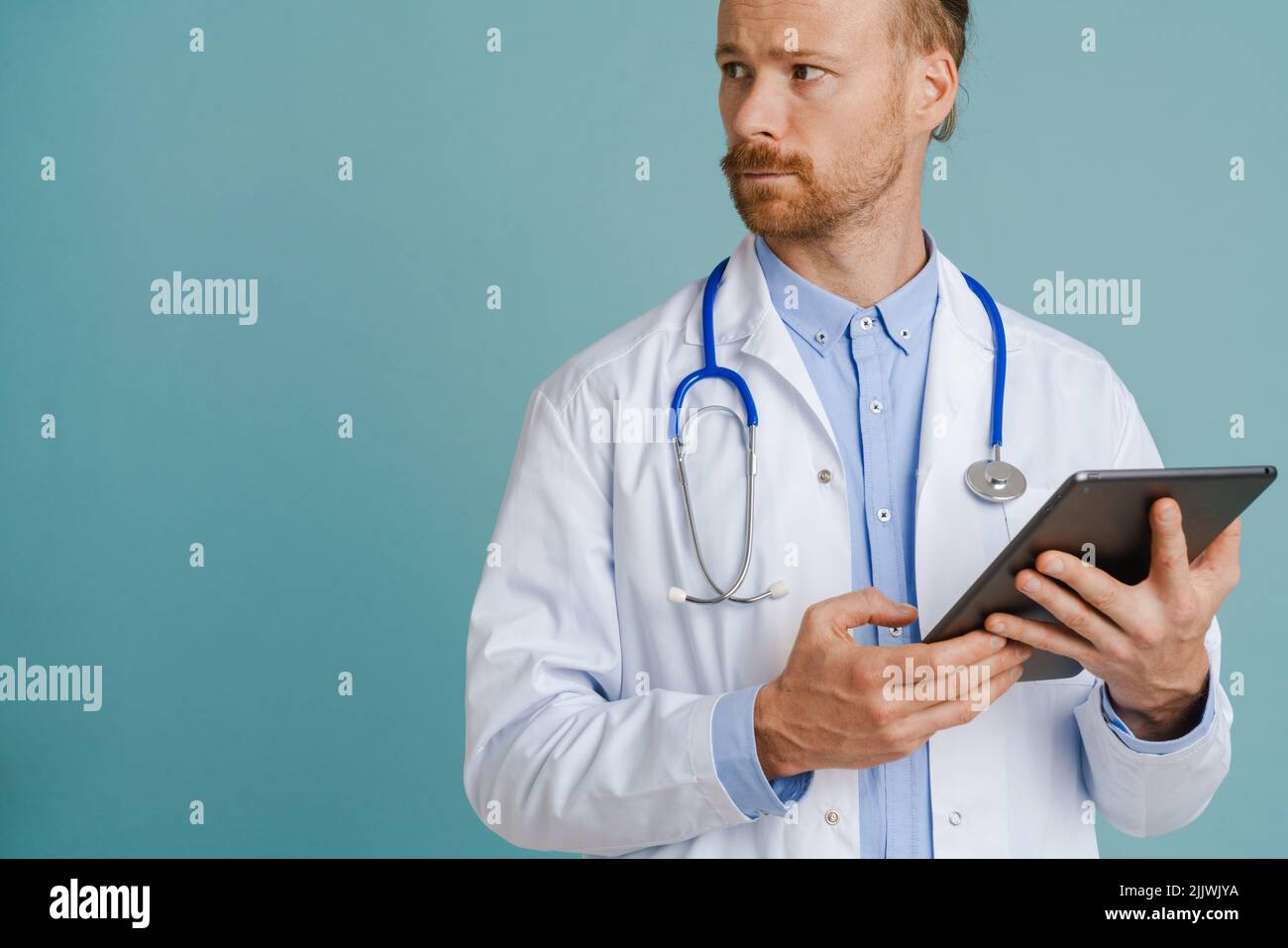White male doctor wearing lab coat using tablet computer isolated over ...